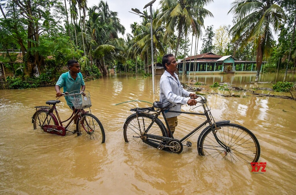Nagaon: People push their cycles through floodwater following the ...